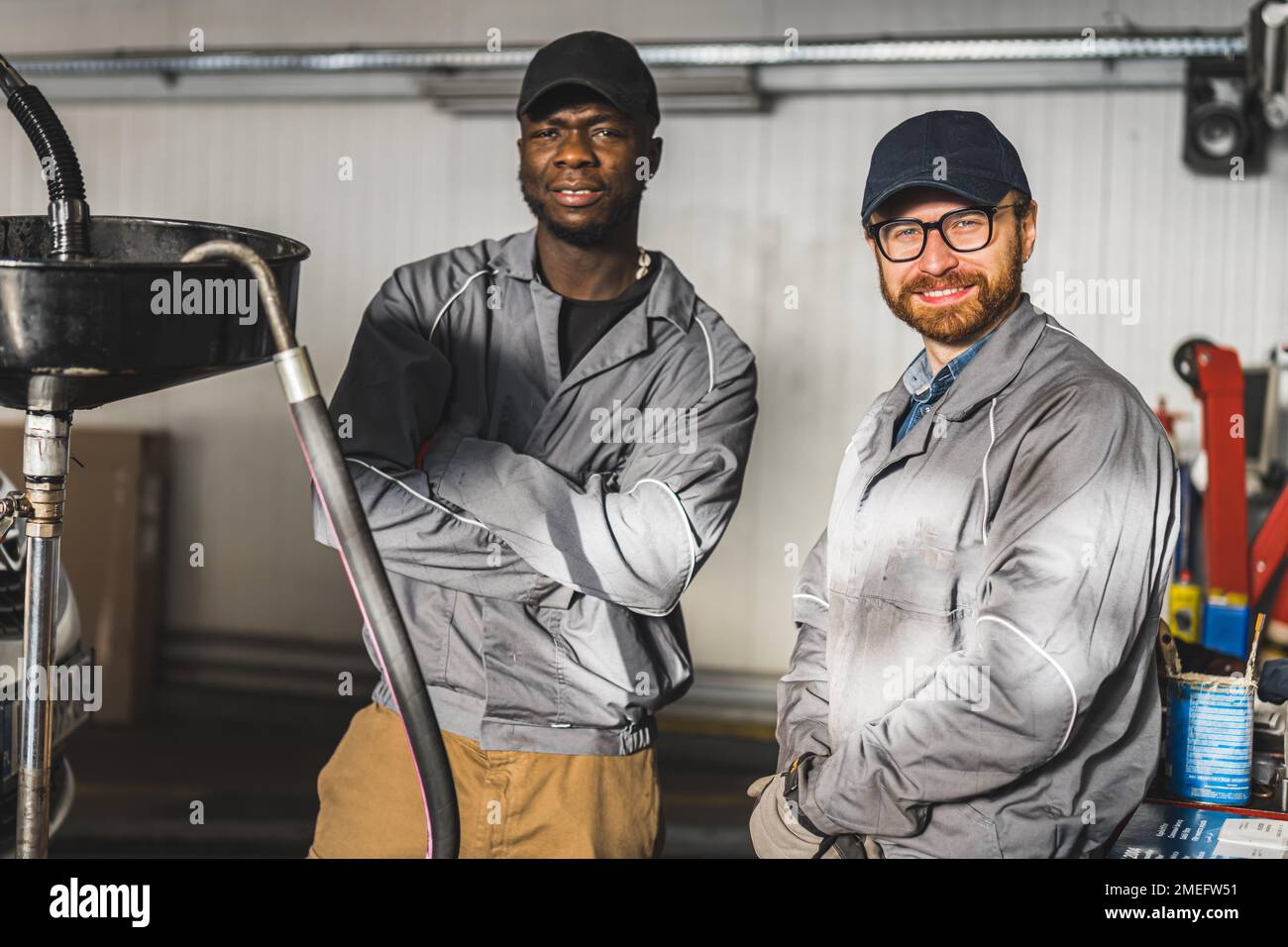 Mechanics posing for the camera while changing engine oil in an auto ...