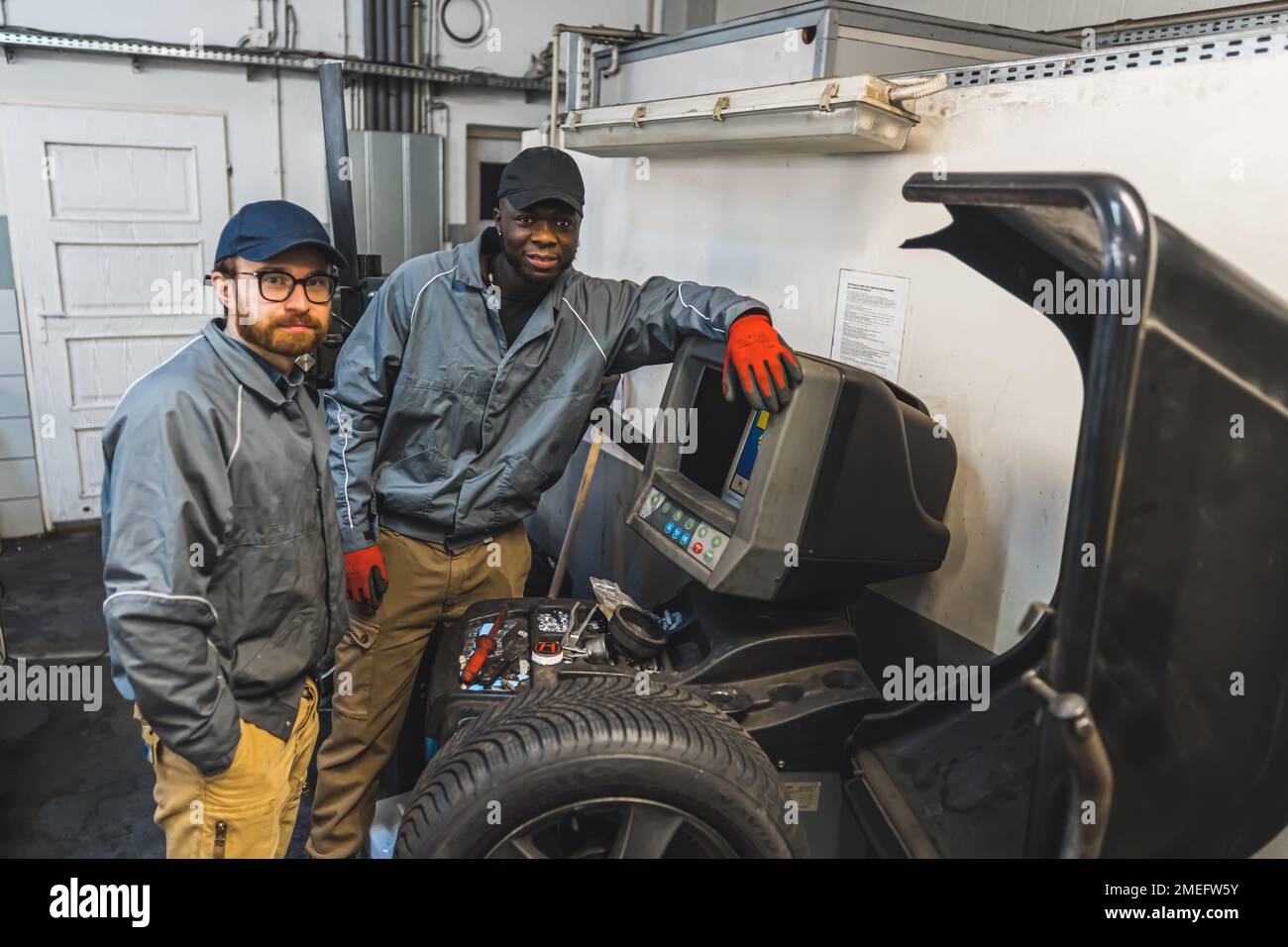 Medium shot of black and white mechanics standing by a computer in a ...