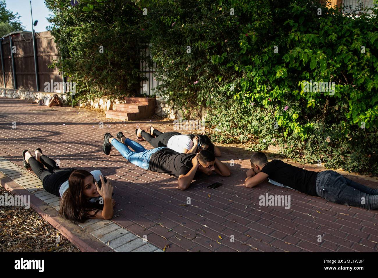 Israelis take cover as a siren sounds a warning of incoming rockets ...