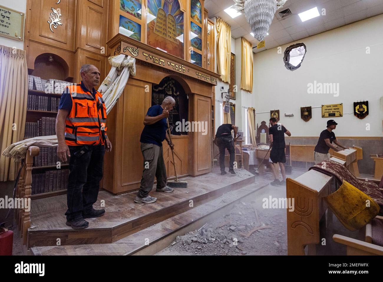 People clean a damaged synagogue after it was by a rocket fired from ...