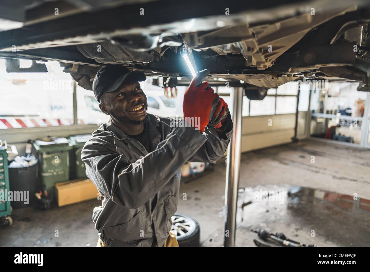 Medium shot of a black mechanic lighting a chassis of a car with a ...