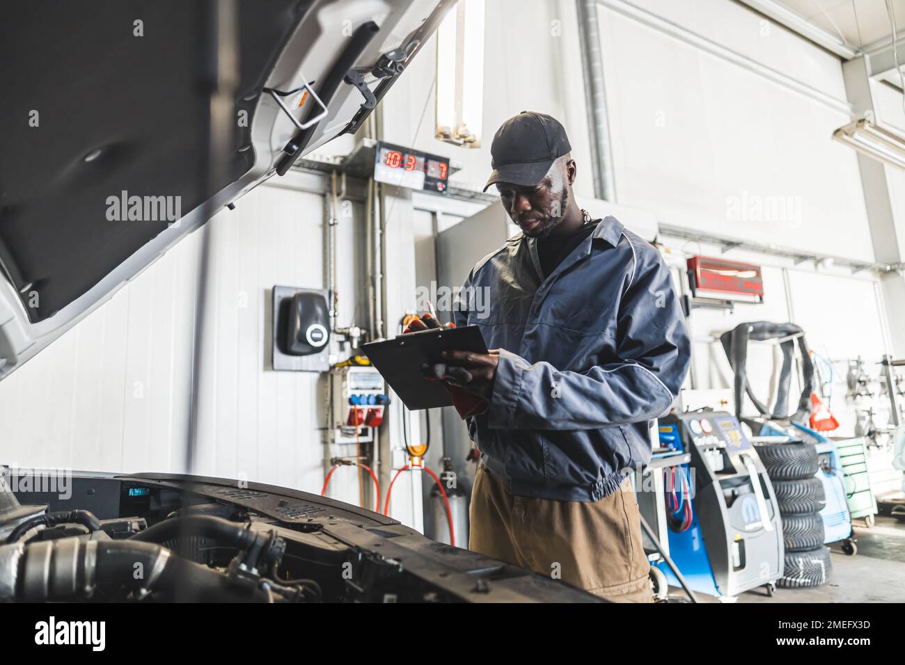 Skilled car mechanic inspects the car engine at the repair facility and ...