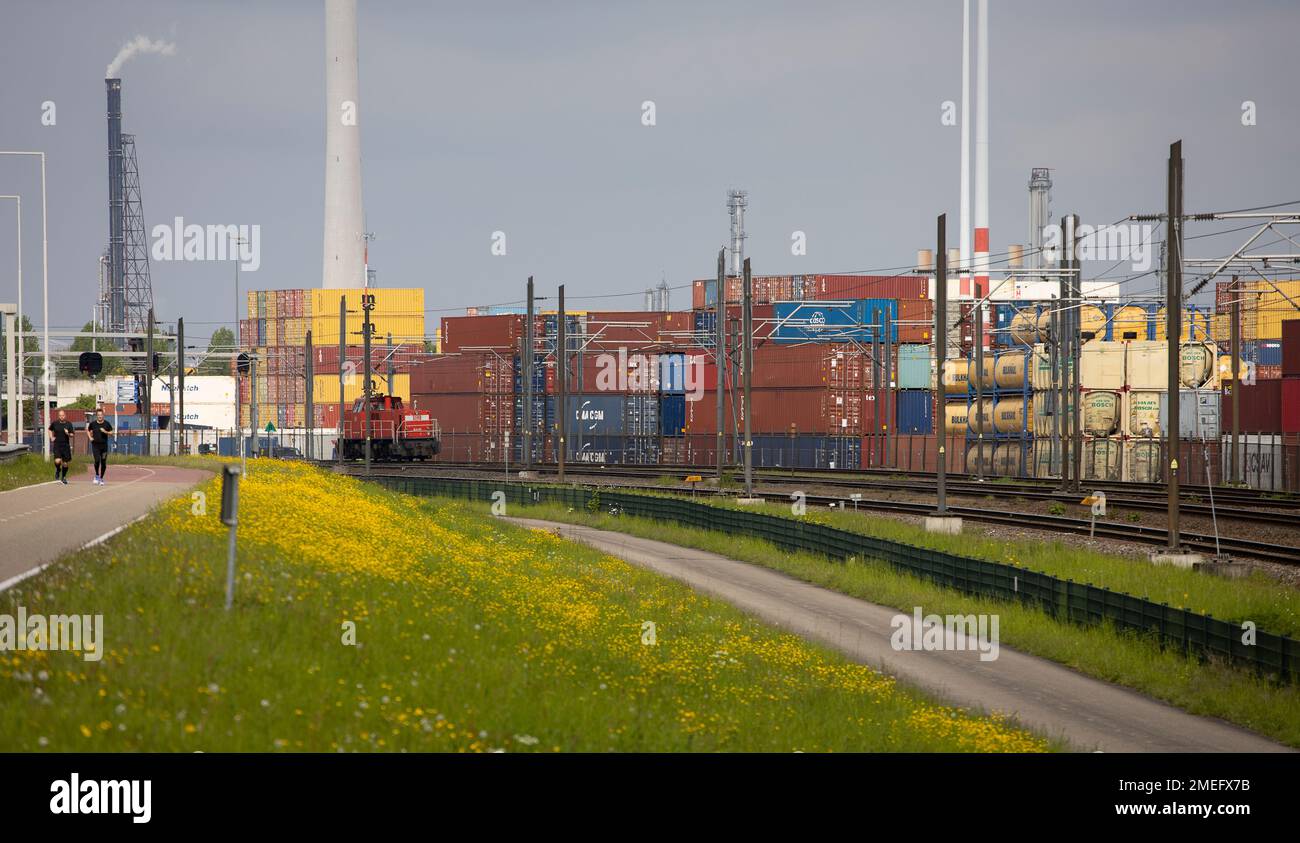 A couple of joggers pass shipping containers at a terminal in the port ...