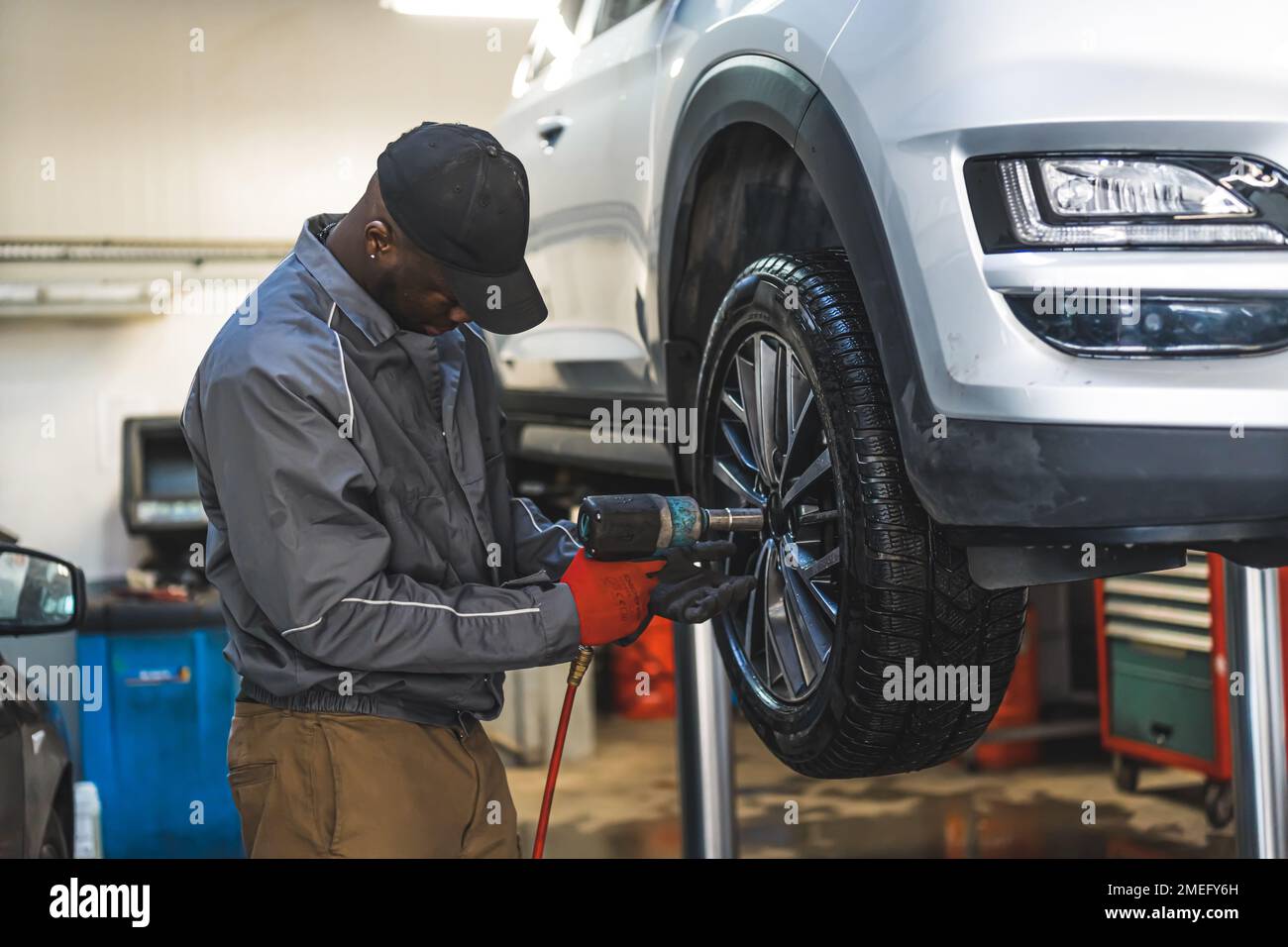 Mechanic changing tyres using an electric wrench car is lifted for a ...