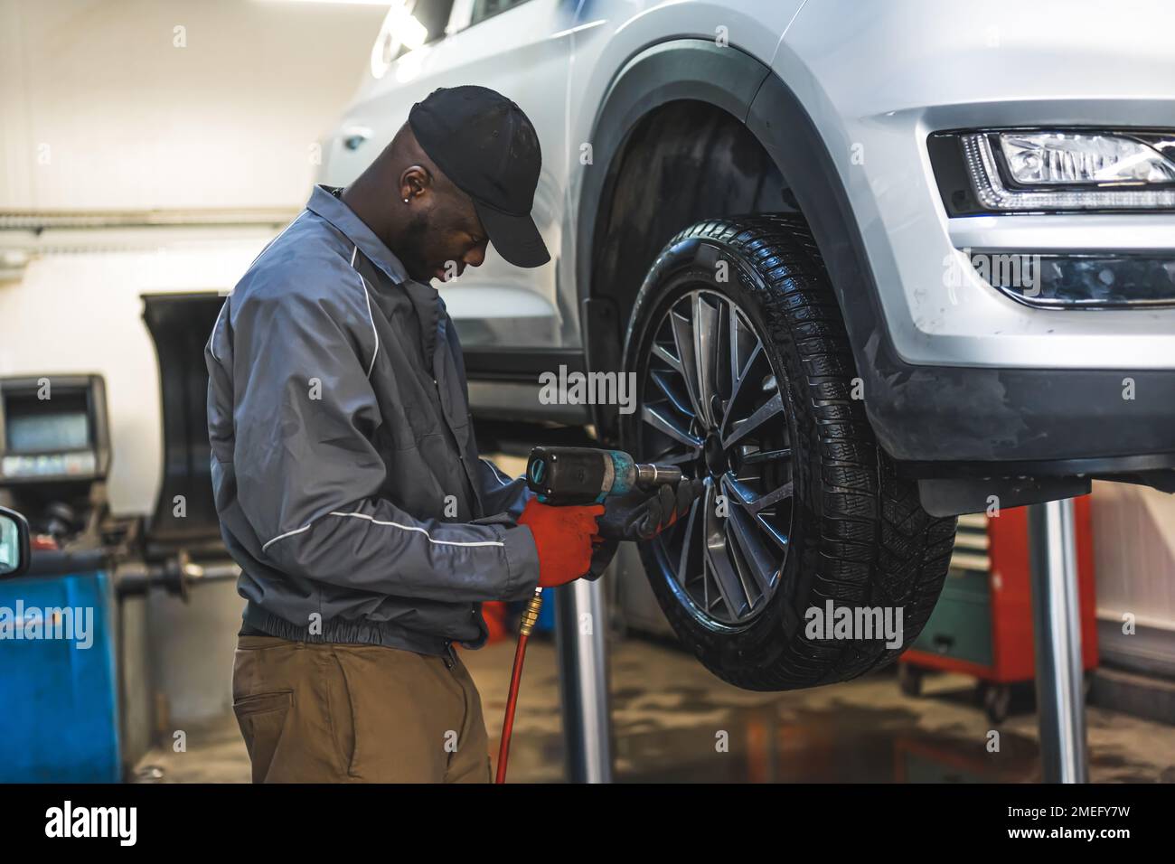 A mechanic working on a lifted-up car - Changing wheels using an ...