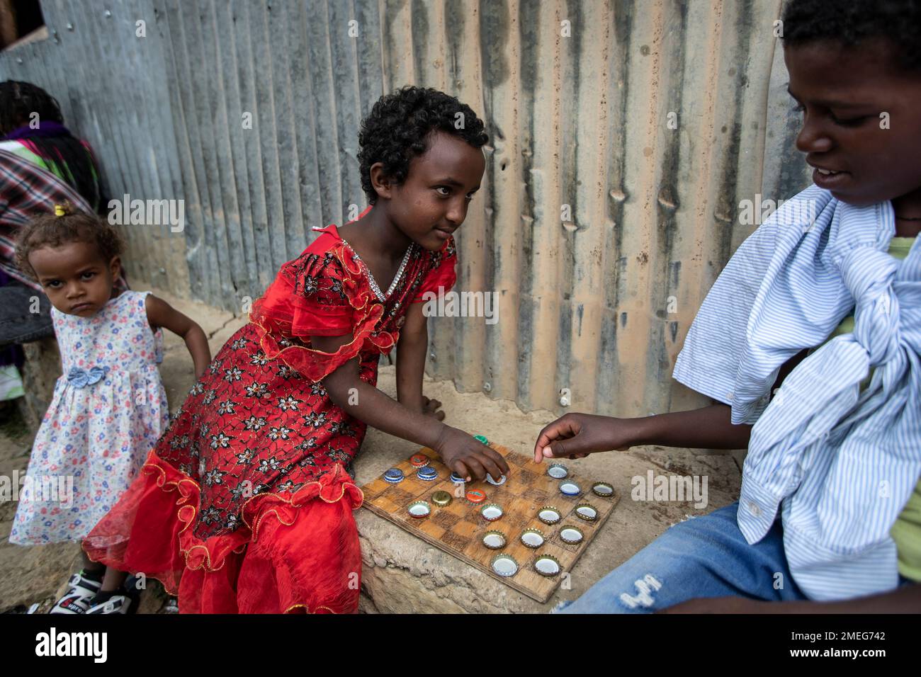 Elena, 7, left, plays a game of checkers using soda bottle tops with ...