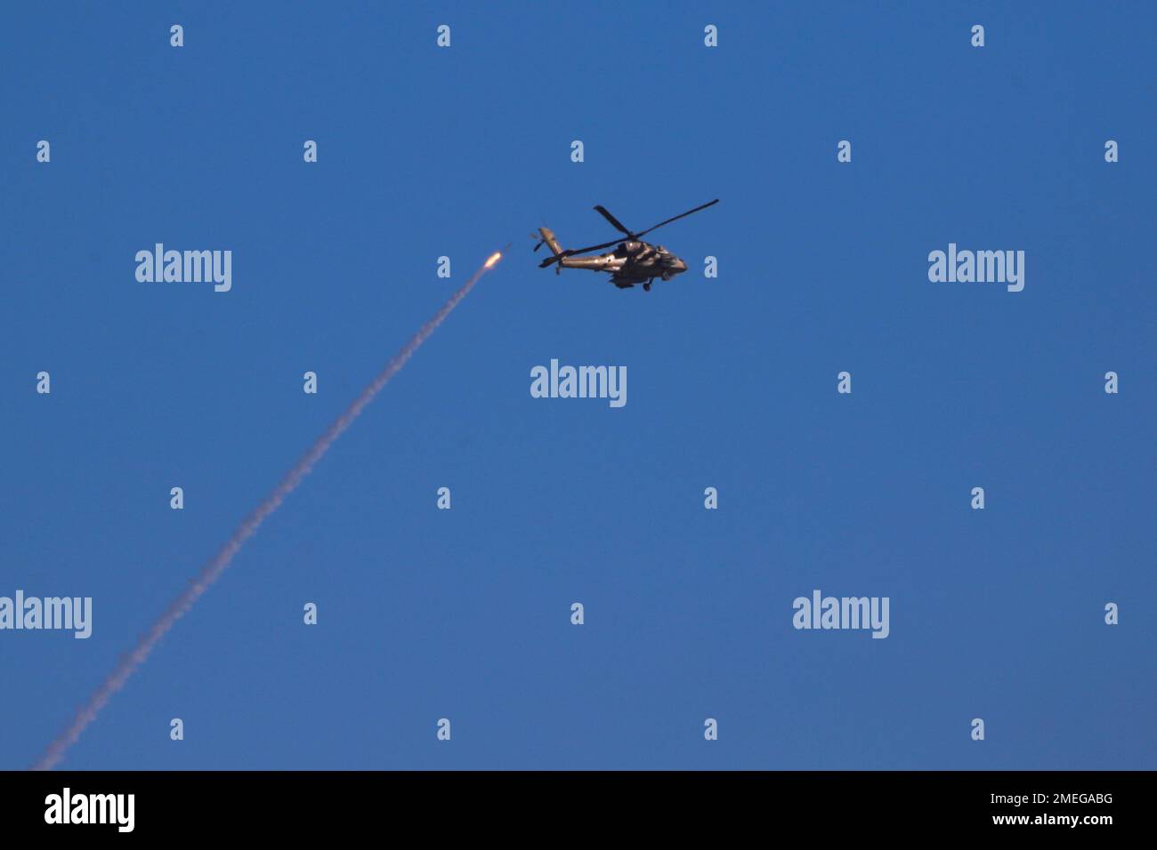 An Israeli attack helicopter flies by an Iron Dome air defense system ...