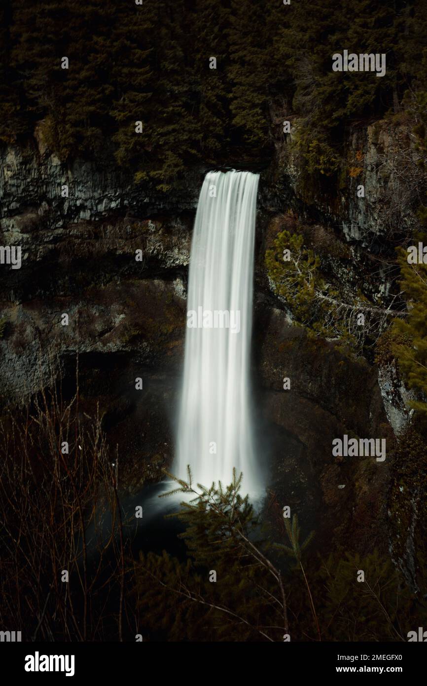 A vertical aerial view of foamy waterfall flowing down the steep rocky ...