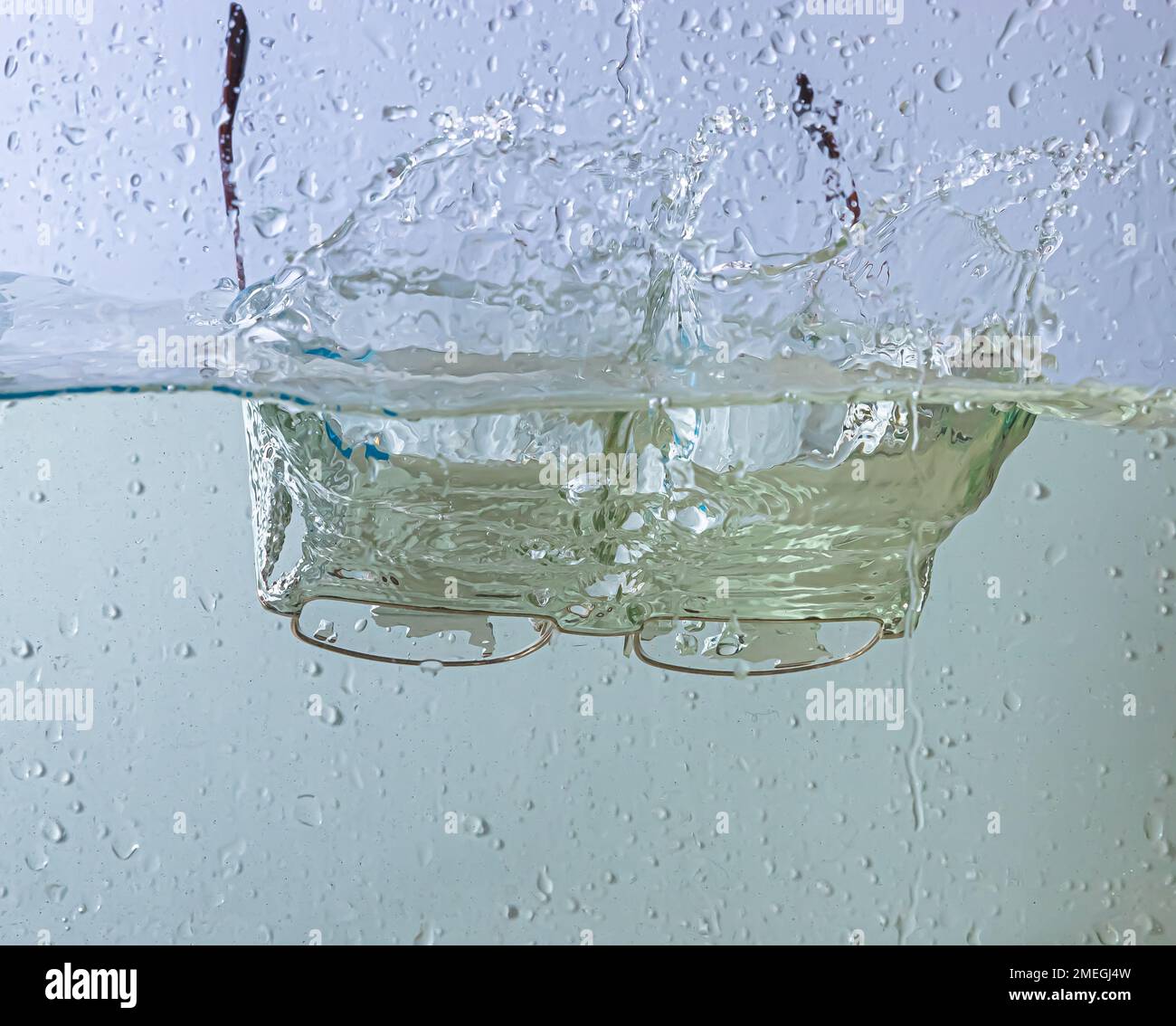 glasses fall into the water. sprays, drops and bubbles Stock Photo - Alamy