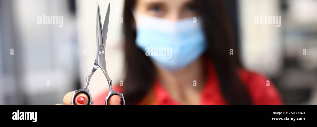 Woman hairdresser in protective mask holds scissors Stock Photo - Alamy
