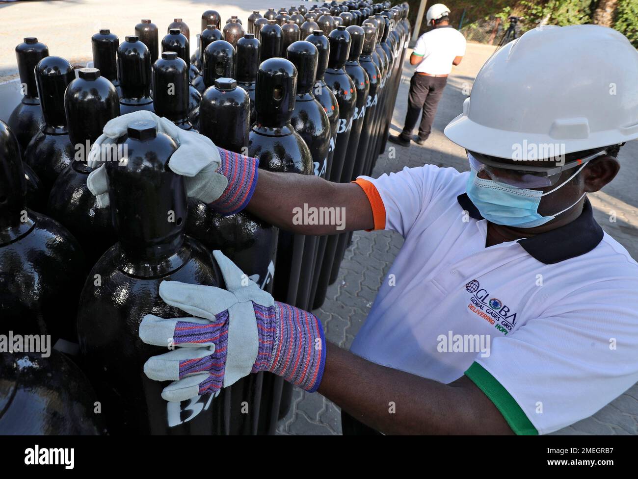 A volunteer checks cylinders of compressed oxygen before shipping them ...