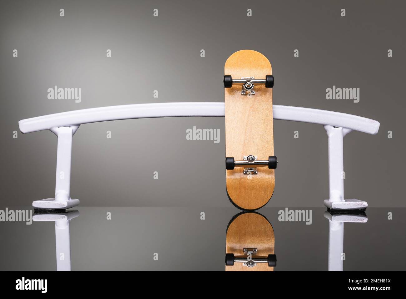 Wooden fingerboard and white metal railing on a gray gradient ...