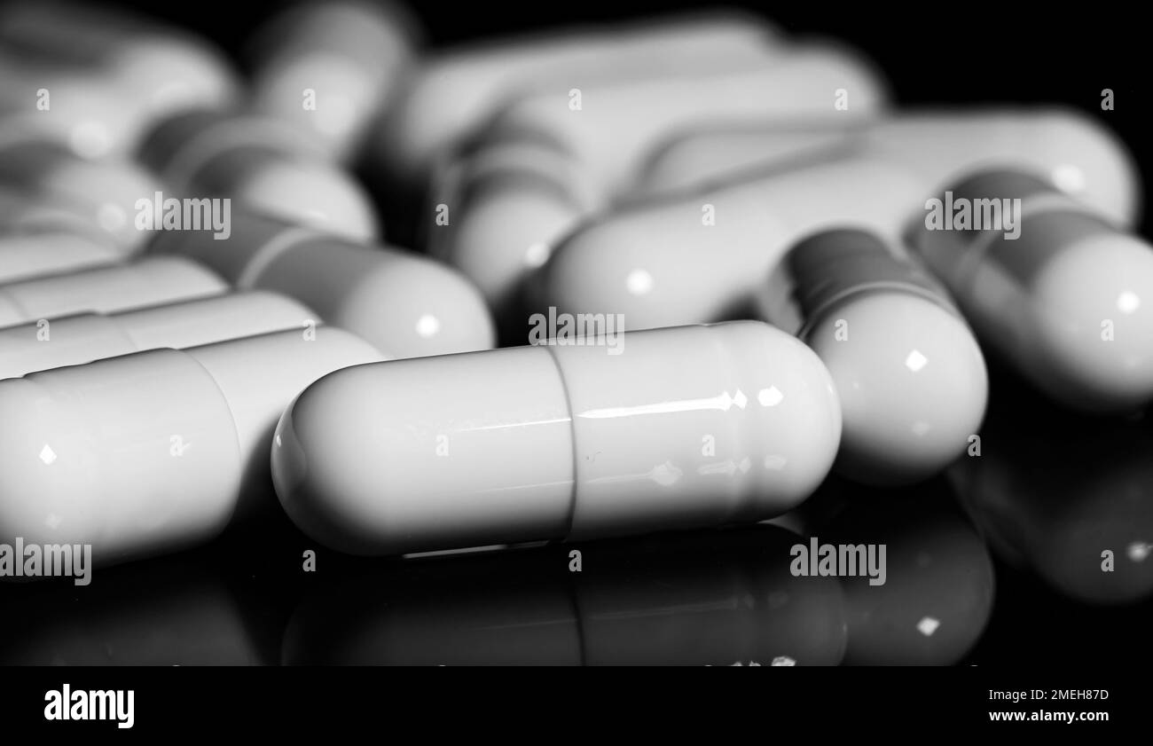 Macro Close up of white painkiller capsule on a reflective black ...