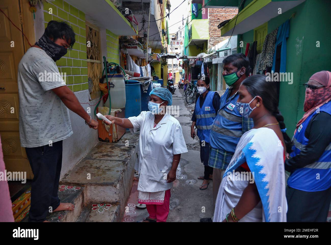 An Indian health worker checks body temperature of a man during a door ...