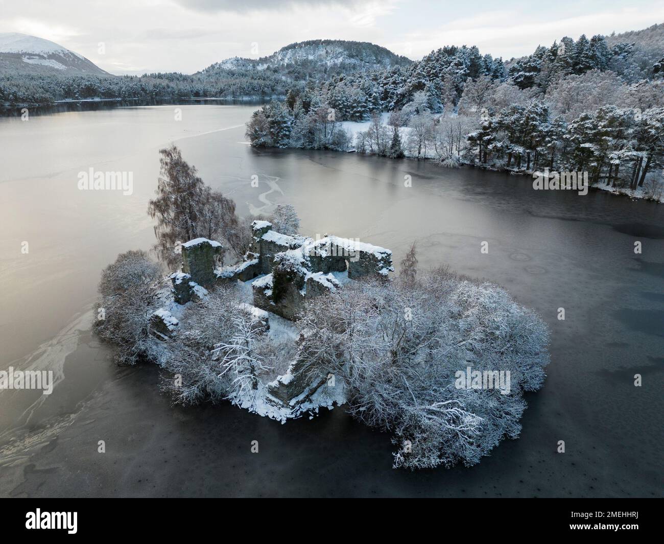 Aerial view of ruined castle in snow on Loch an Eilein in Cairngorms ...