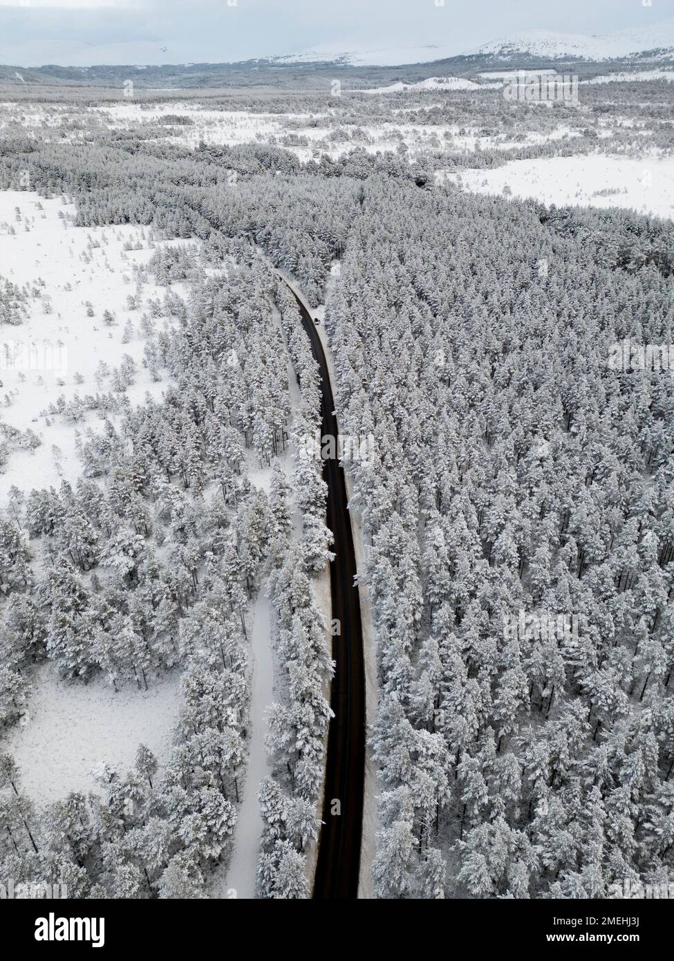 Aerial view of road in snow Rothiemurchus forest in Cairngorms national ...