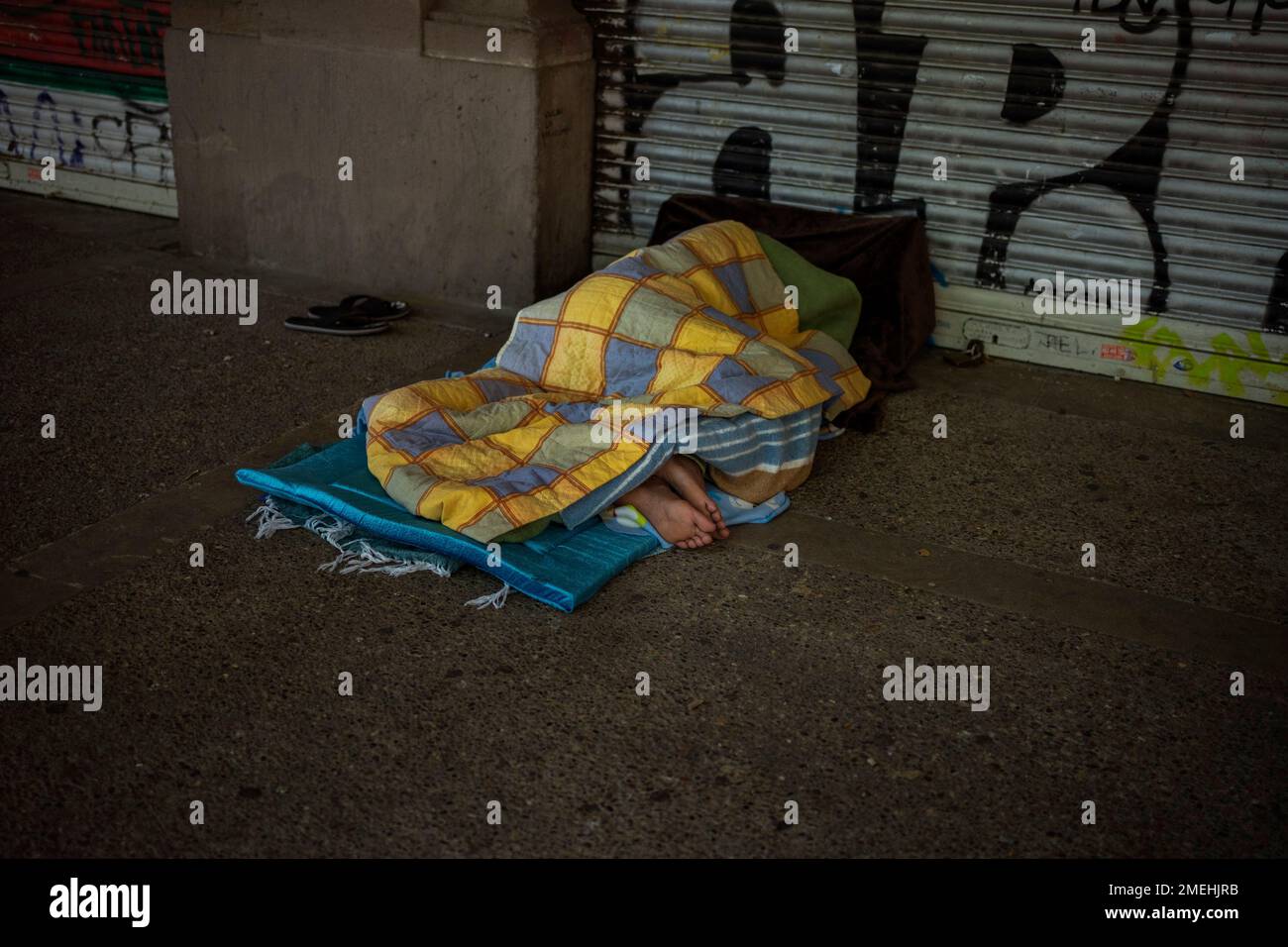A homeless person sleeps on the ground of a street in downtown ...