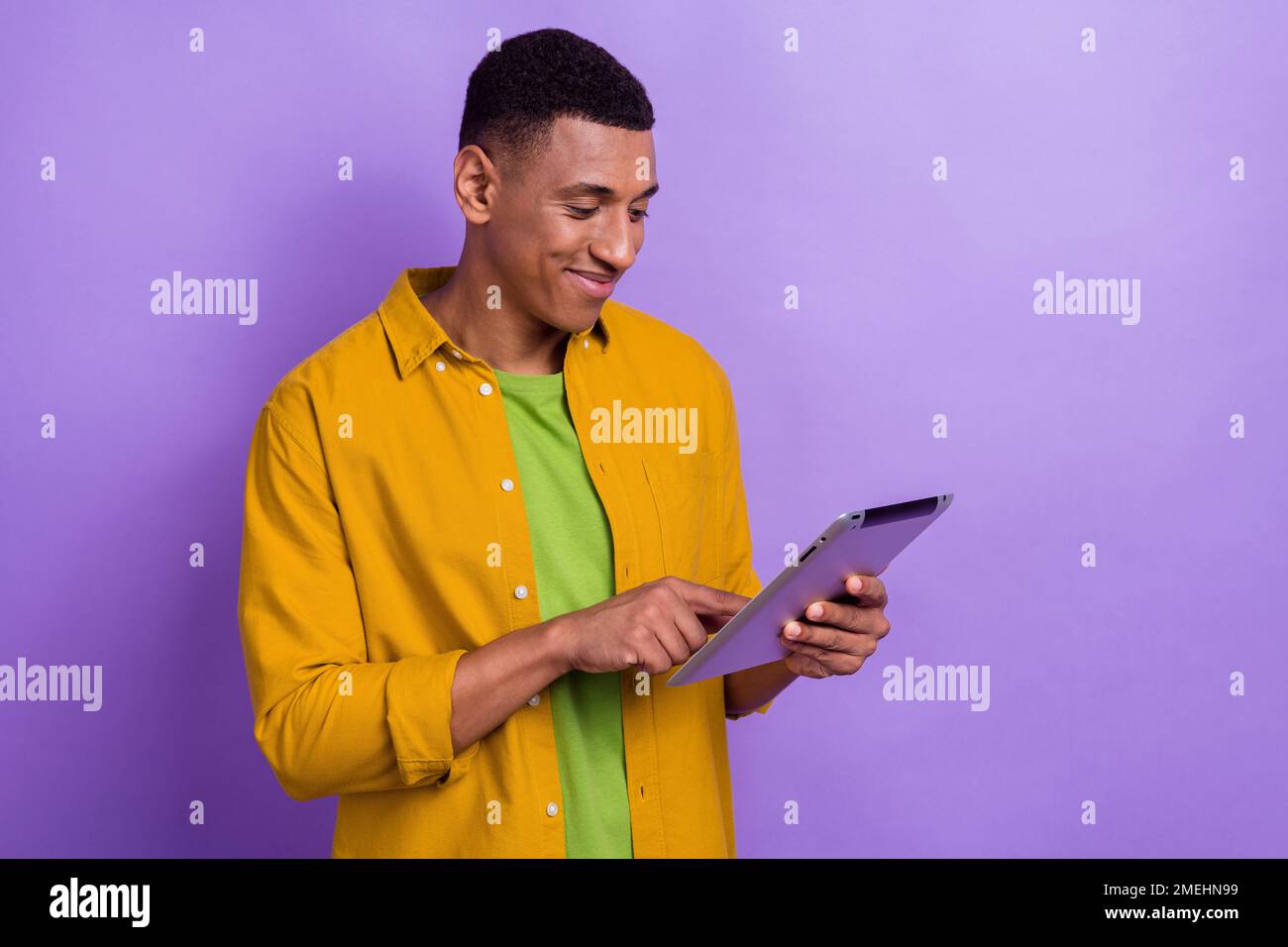 Photo portrait of nice young guy holding tablet gadget typing scrolling ...