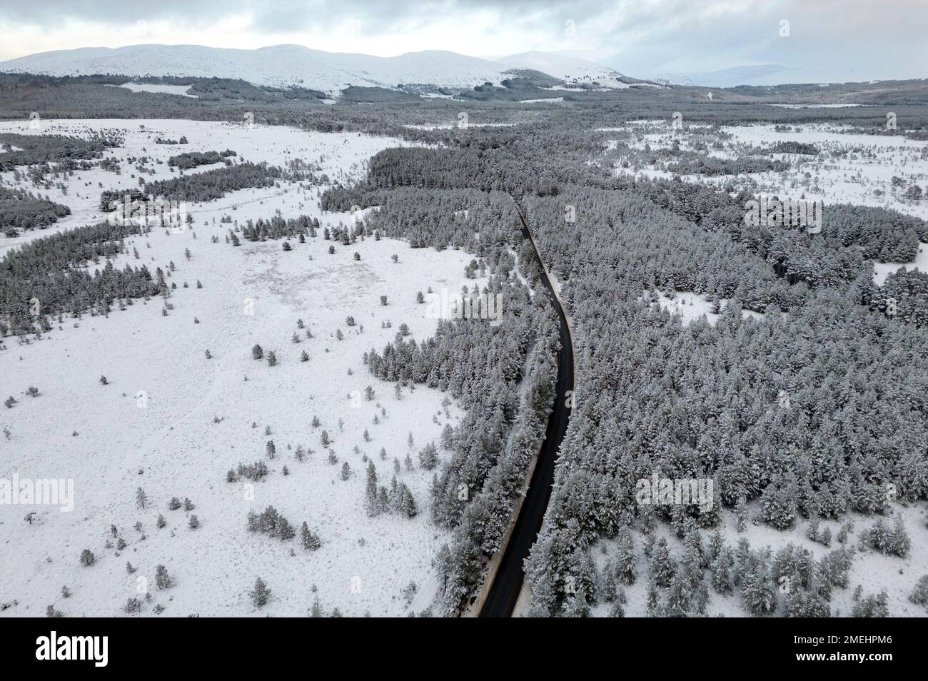 Aerial view of road in snow Rothiemurchus forest in Cairngorms national ...