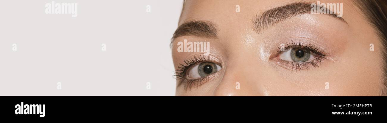 Cropped image of female face, eyes over grey background. Natural makeup ...