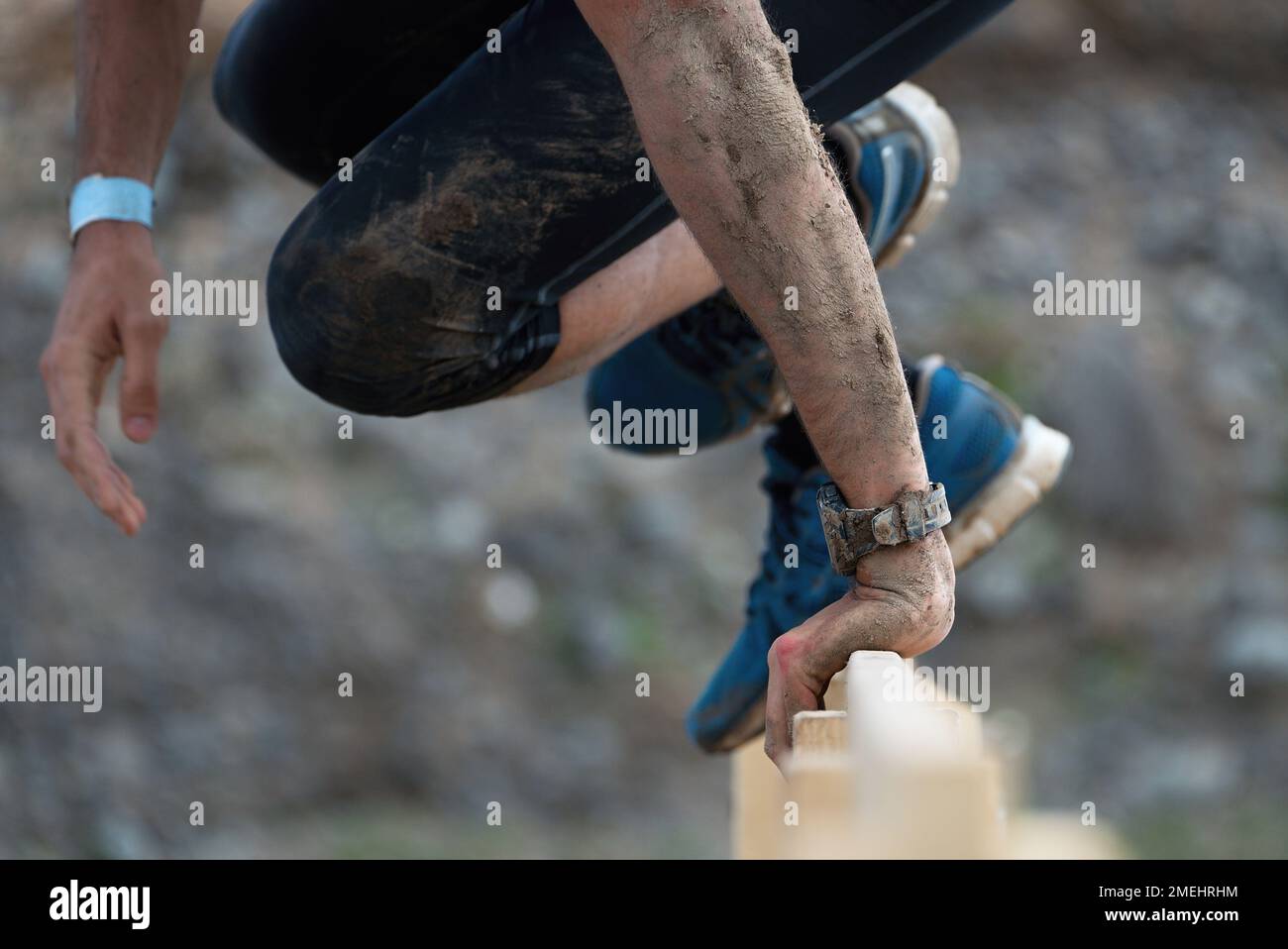 Mud race runners participant jumps over obstacles Stock Photo - Alamy