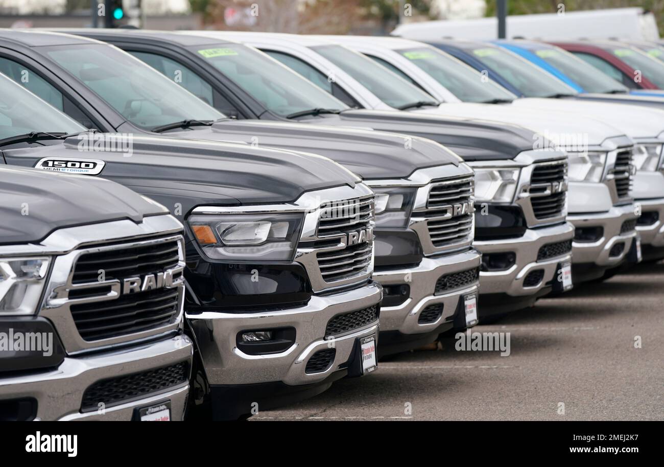 A long row of unsold 2021 Ram pickups sits at a Dodge dealership in ...