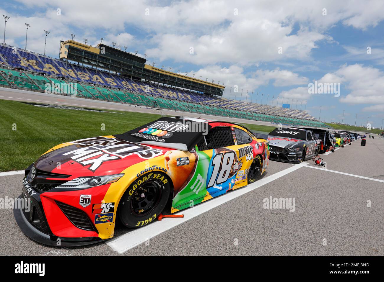 Kyle Busch's 18 car and others are parked along pit road before the ...