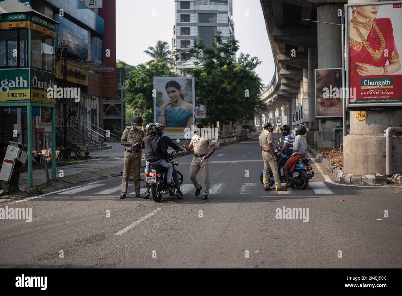 Indian policemen check the credentials of commuters as they enforce a ...