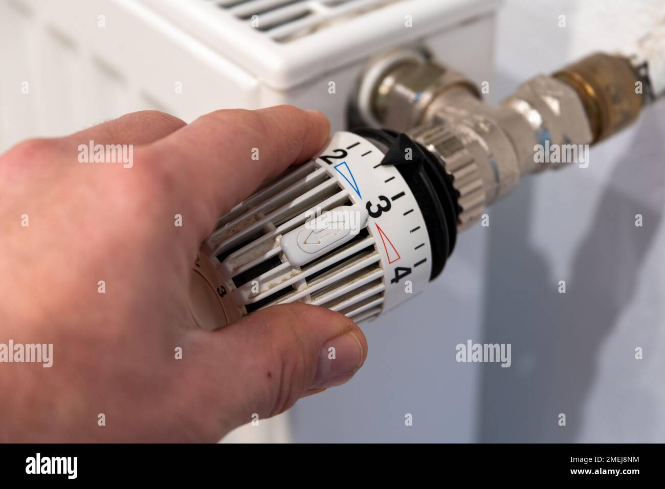 Male hand turns a radiator thermostat Stock Photo - Alamy