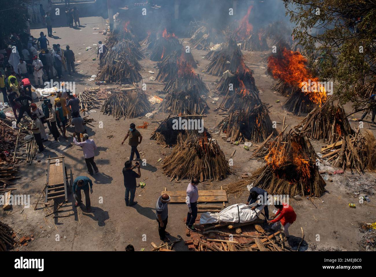 Multiple funeral pyres of victims of COVID-19 burn at a ground that has ...