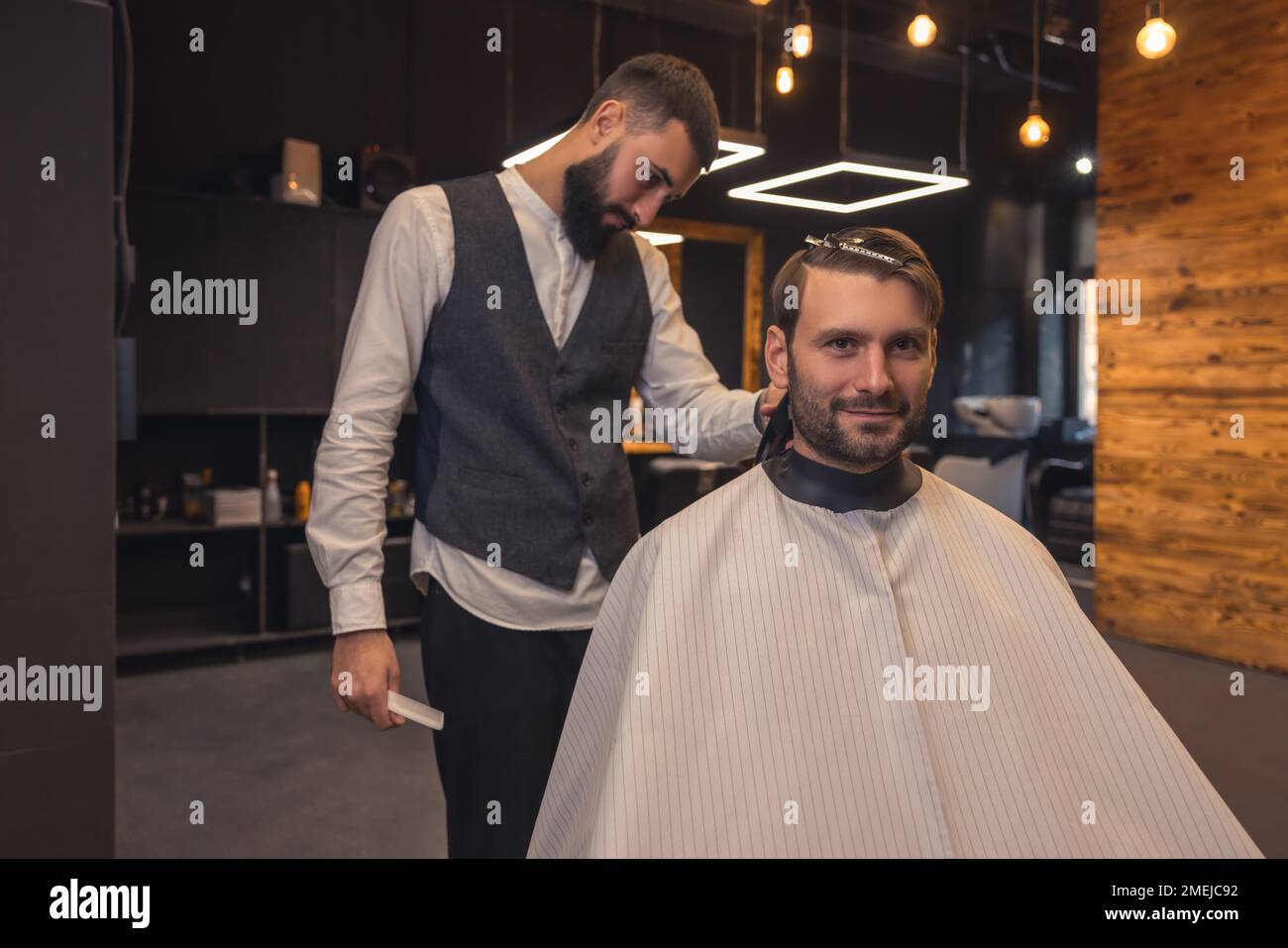 Male barber checking the quality of the haircut and looking ...