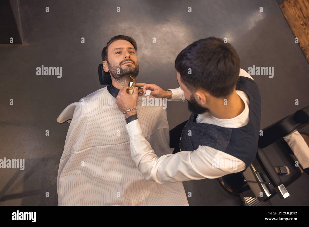 Barber trimming the clients beard Stock Photo - Alamy
