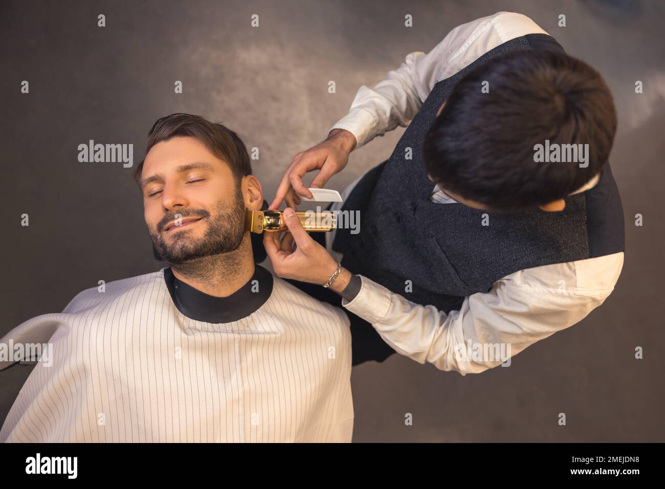 Barber trimming the clients beard Stock Photo - Alamy
