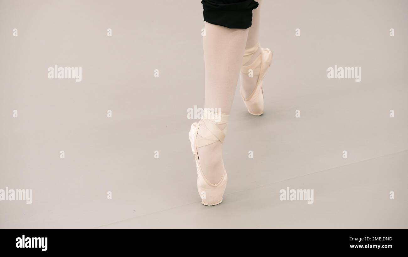 A closeup of the ballerina's feet standing in pointe in ballet slippers ...