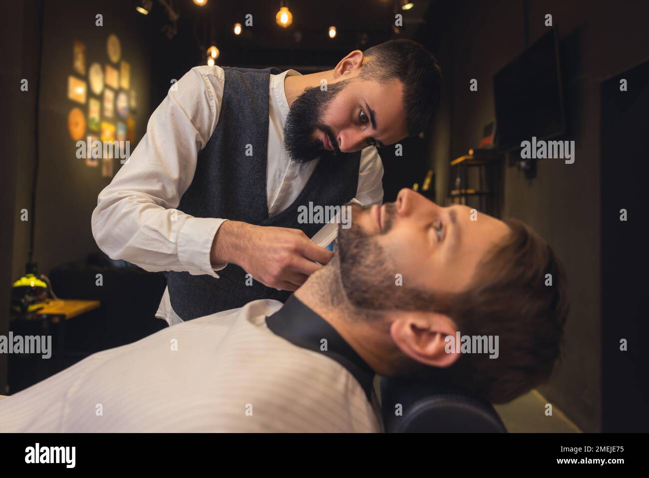 Professional barber carefully trimming the clients beard Stock Photo - Alamy