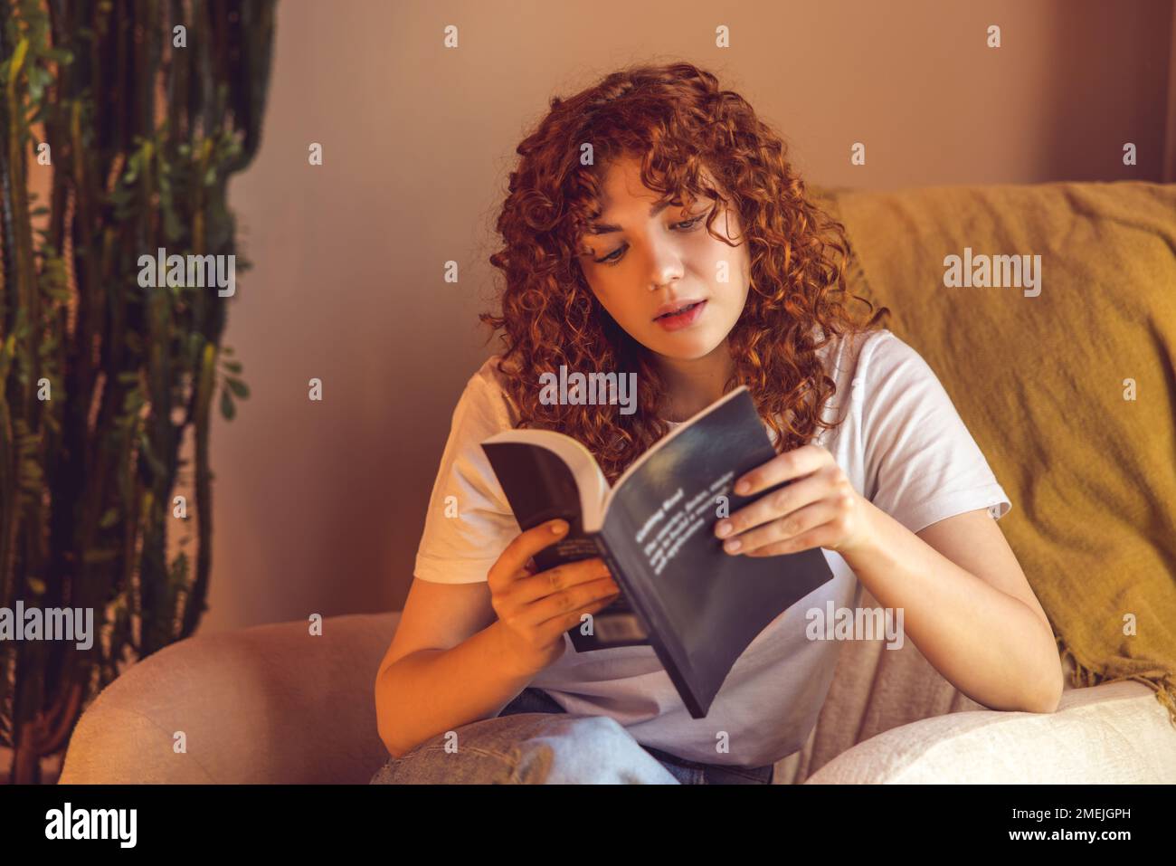 Ginger curly-haired girl reading a book Stock Photo - Alamy