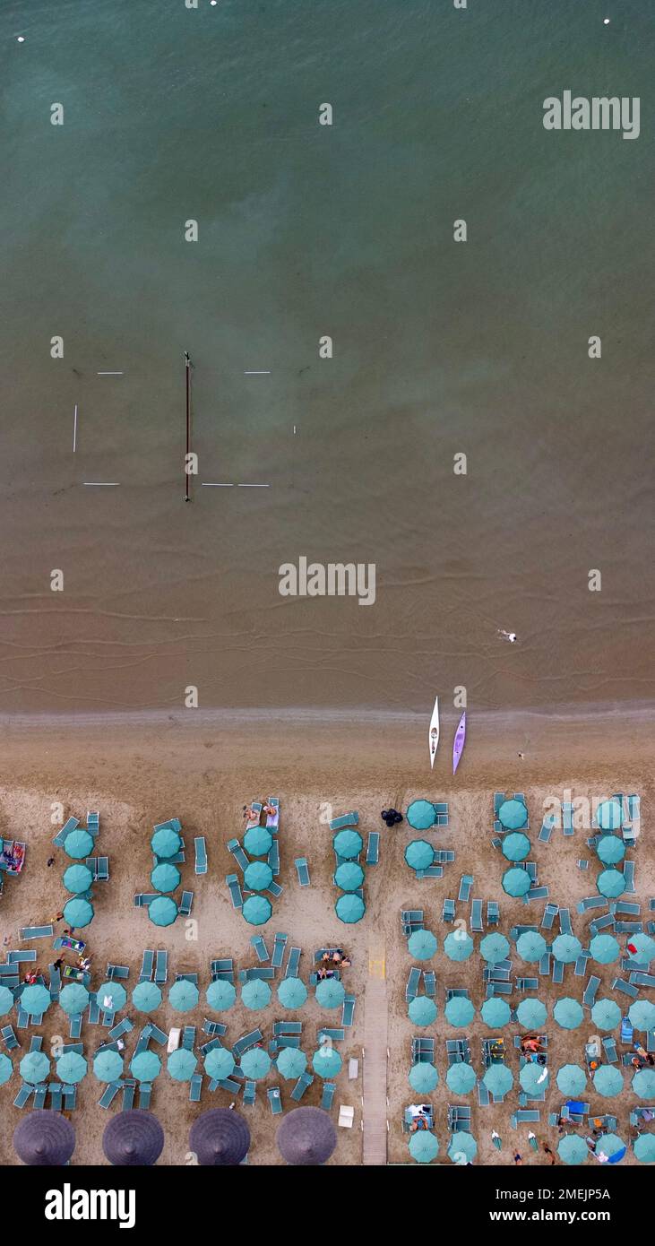 An aerial view of the beach with parasols and chairs with the sea waves ...