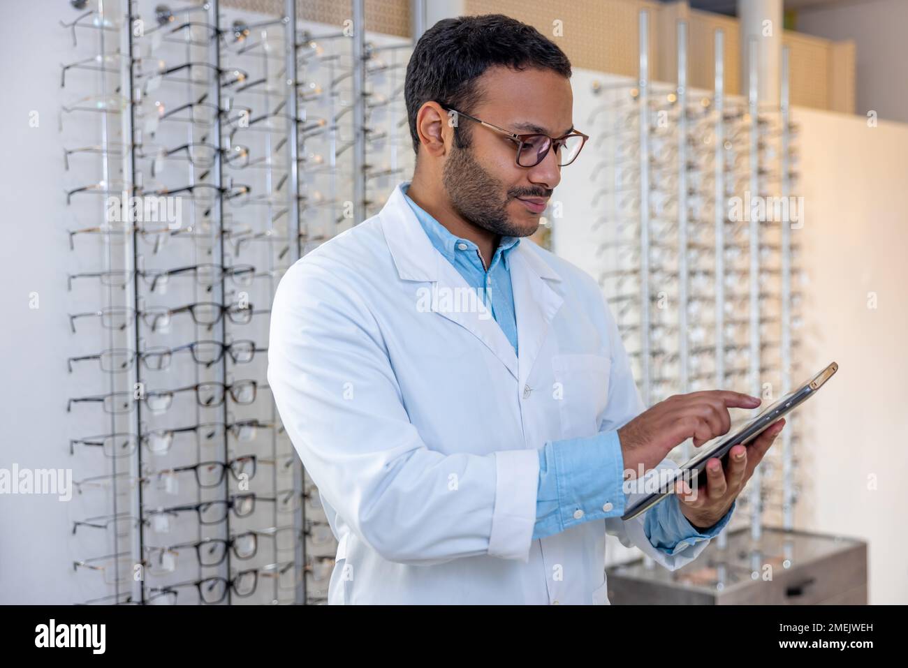 Male optometrist standing near the show-case with eyeglasses Stock ...