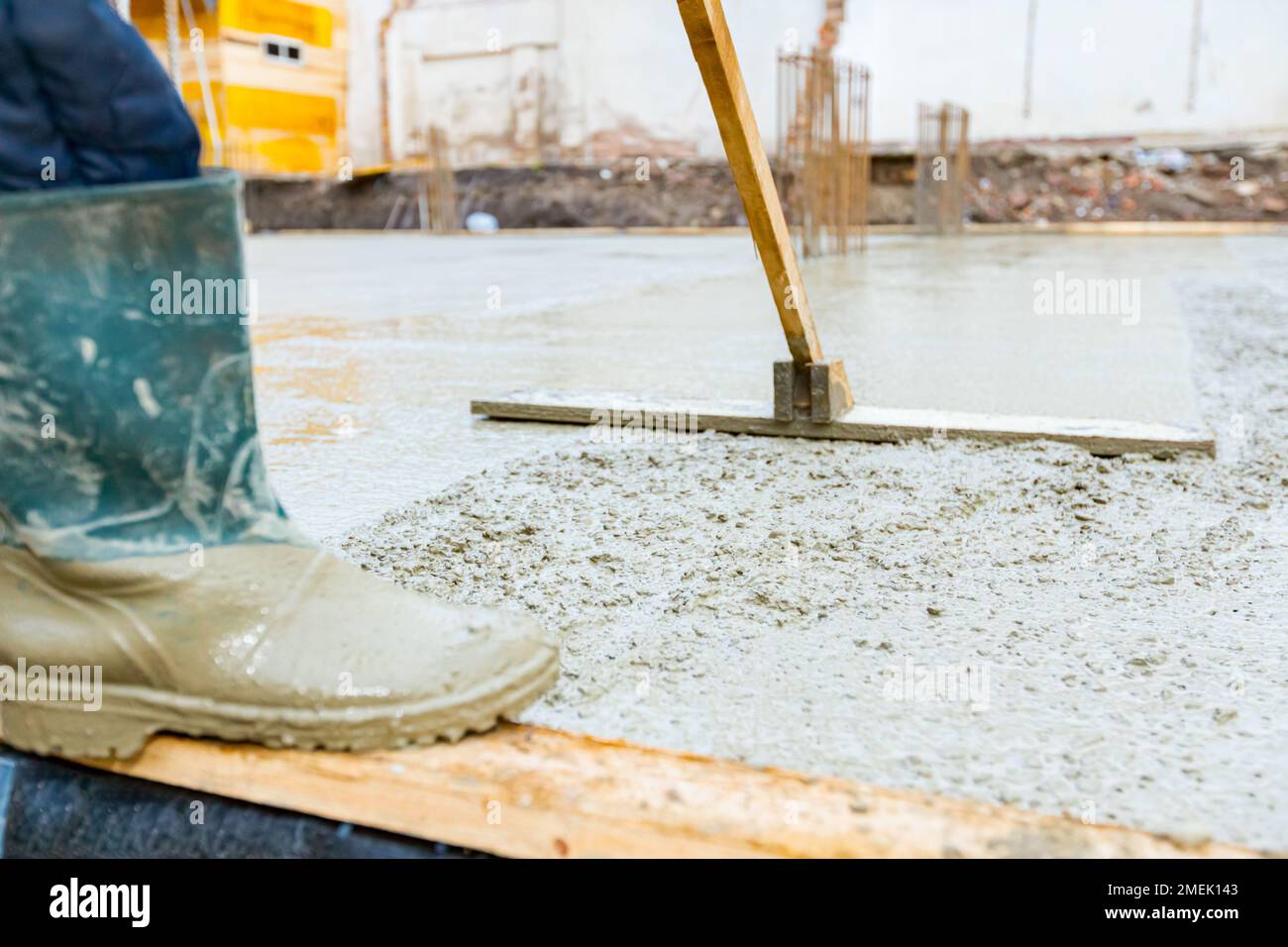 Rigger in rubber boots, worker is using wooden handmade handcraft tool ...