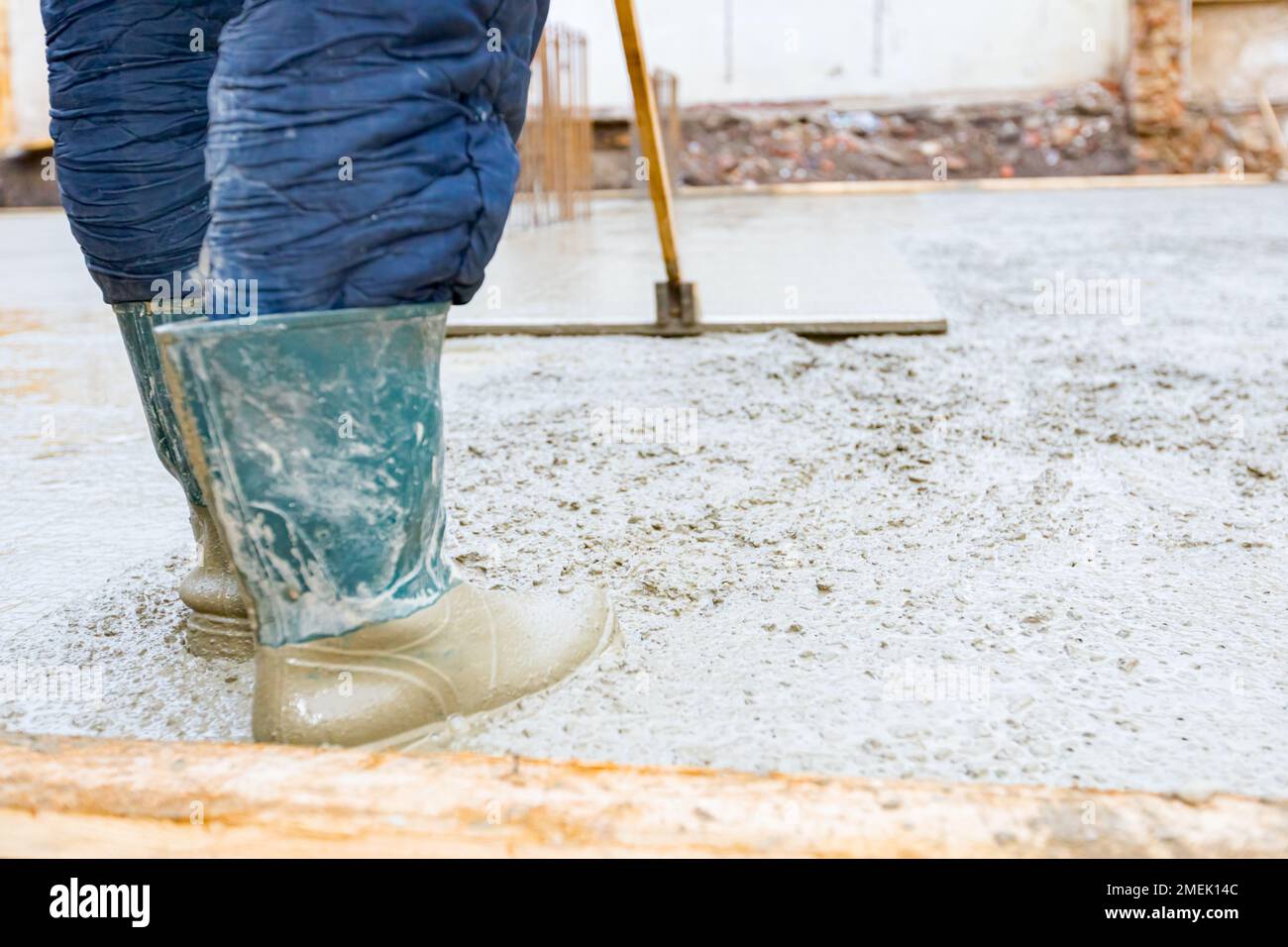 Rigger in rubber boots, worker is using wooden handmade handcraft tool ...
