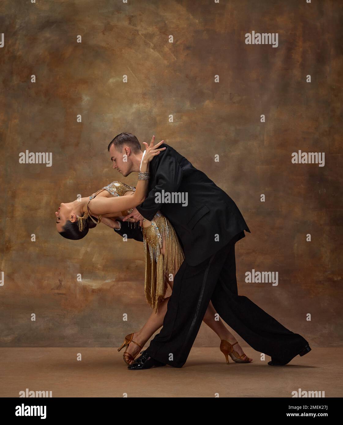 Passionate man and woman, professional dancers in stylish stage costumes performing ballroom ...