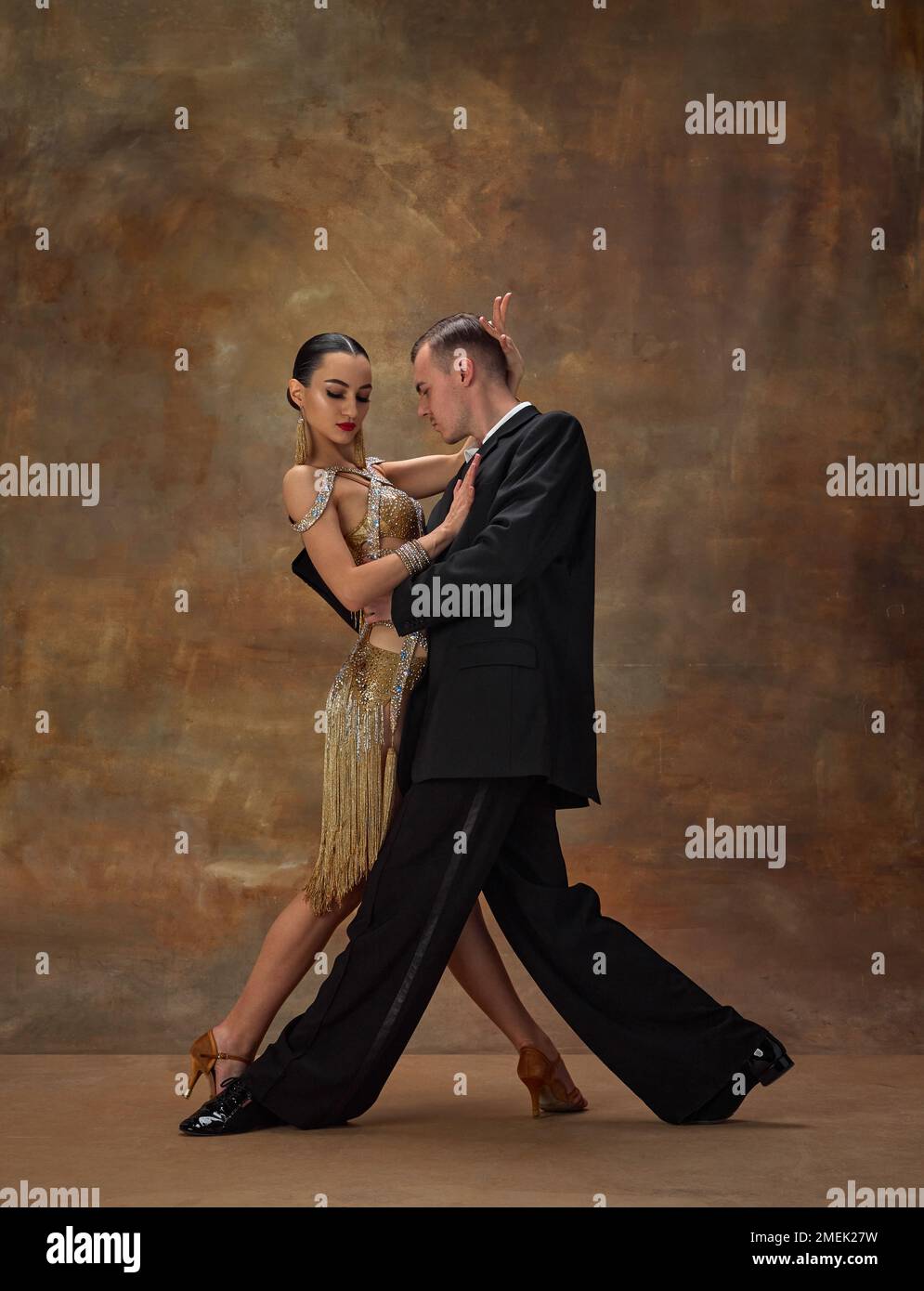 Man and woman, professional tango dancers in stylish, beautiful stage costumes performing over ...