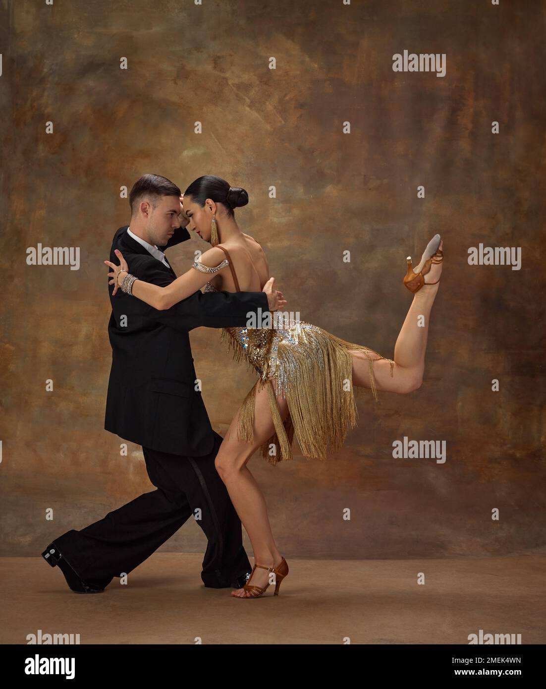 Man and woman, professional tango dancers in stylish, beautiful stage costumes performing over ...