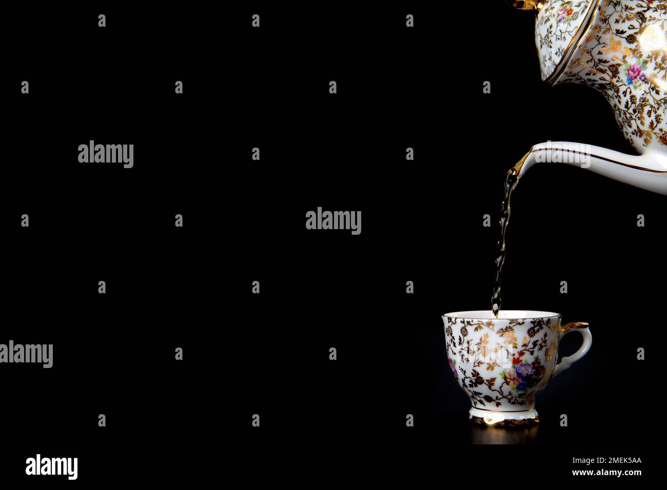 Pouring hot tea in vintage cup on black background, liquid movement in ...