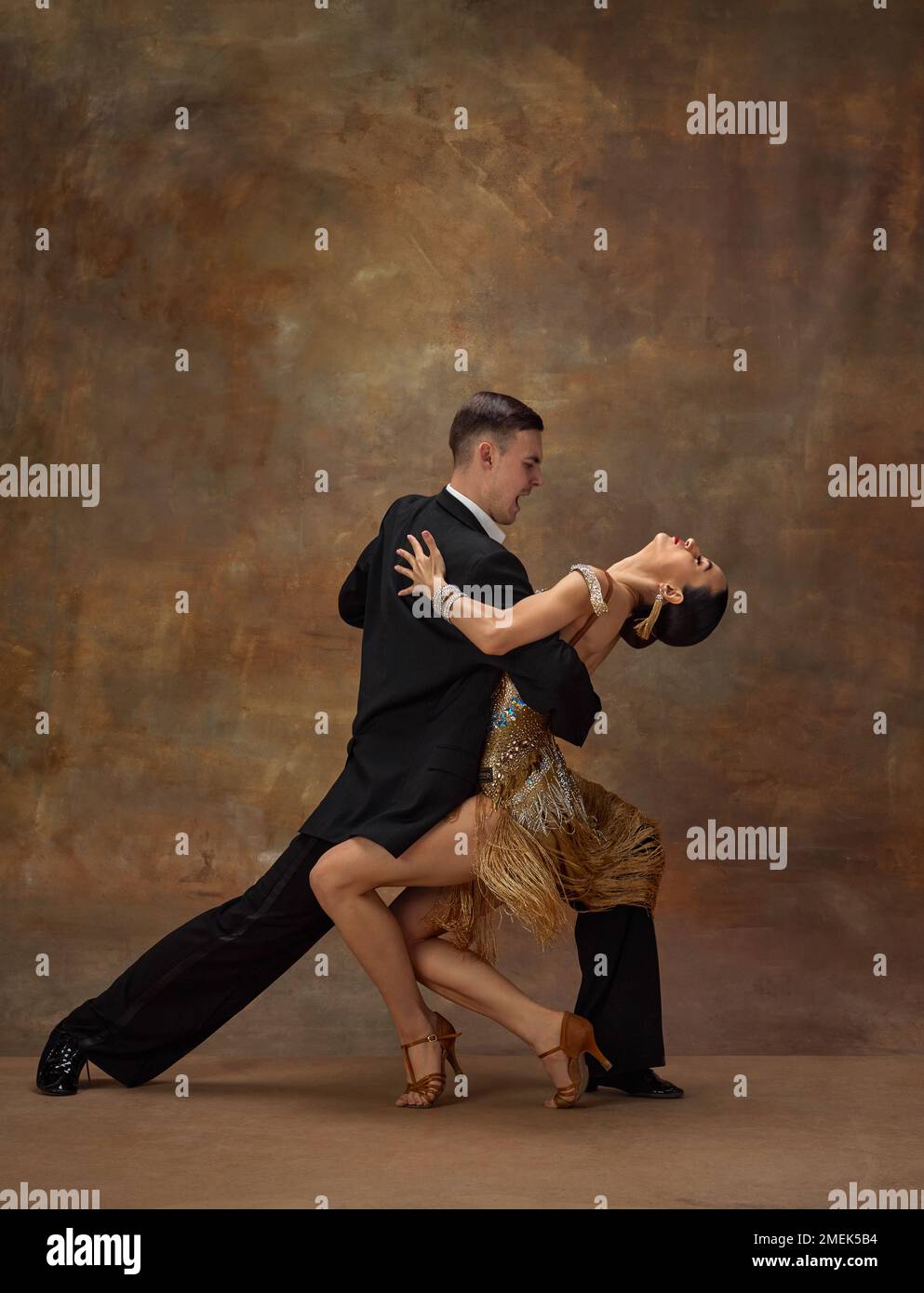 Man and woman, professional tango dancers in stylish, beautiful stage costumes performing over ...