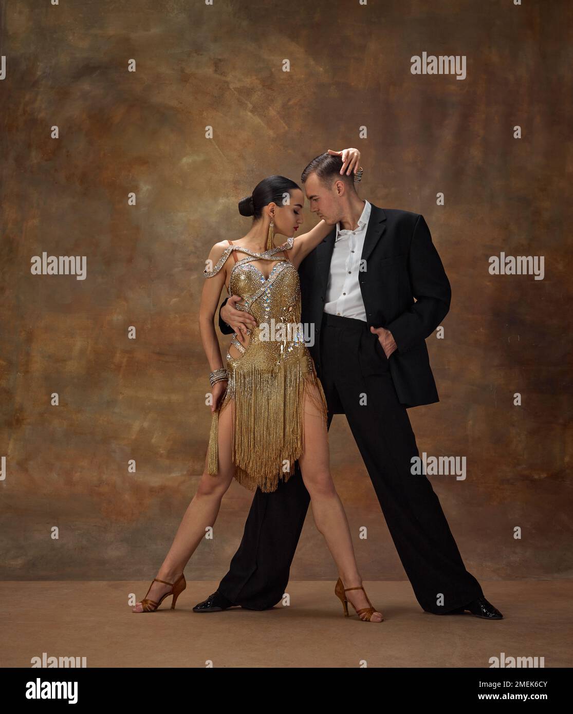Man and woman, professional tango dancers in stylish, beautiful stage costumes performing over ...