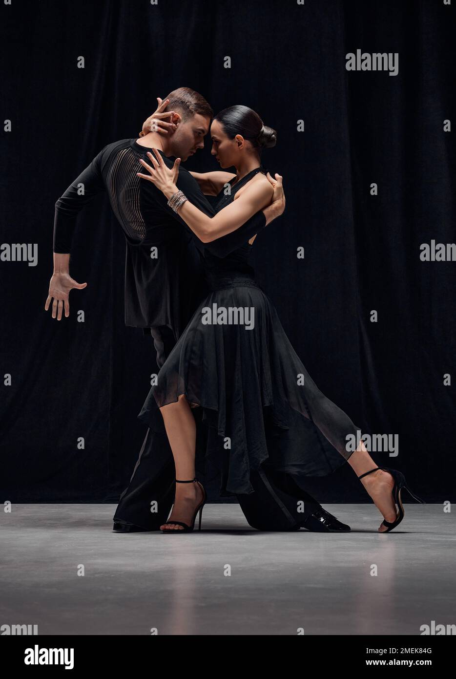 Passion, romance, emotions. Man and woman, professional tango dancers performing in black stage ...
