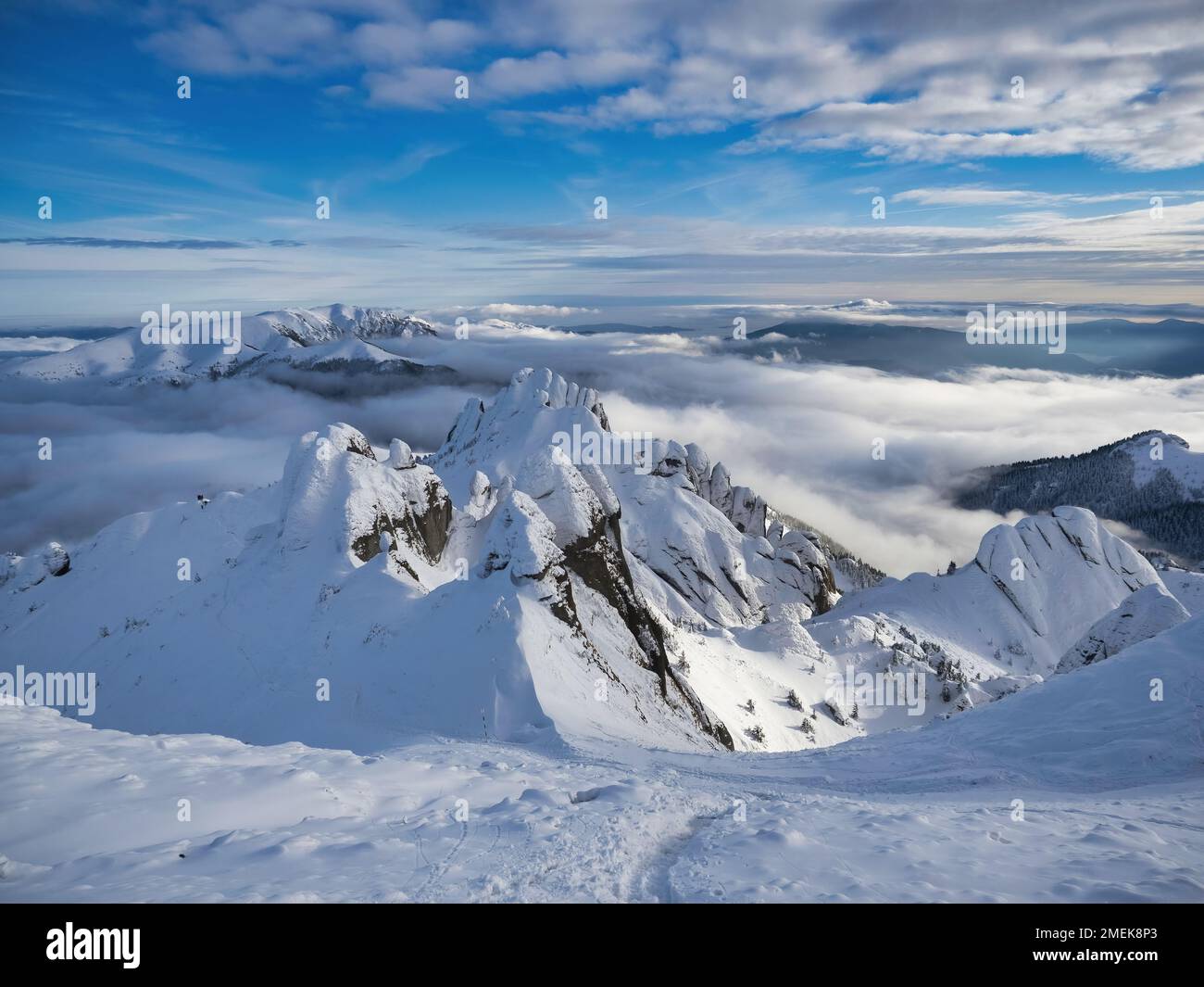 Aerial view of distant mountain peaks above clouds in clear sunny blue ...