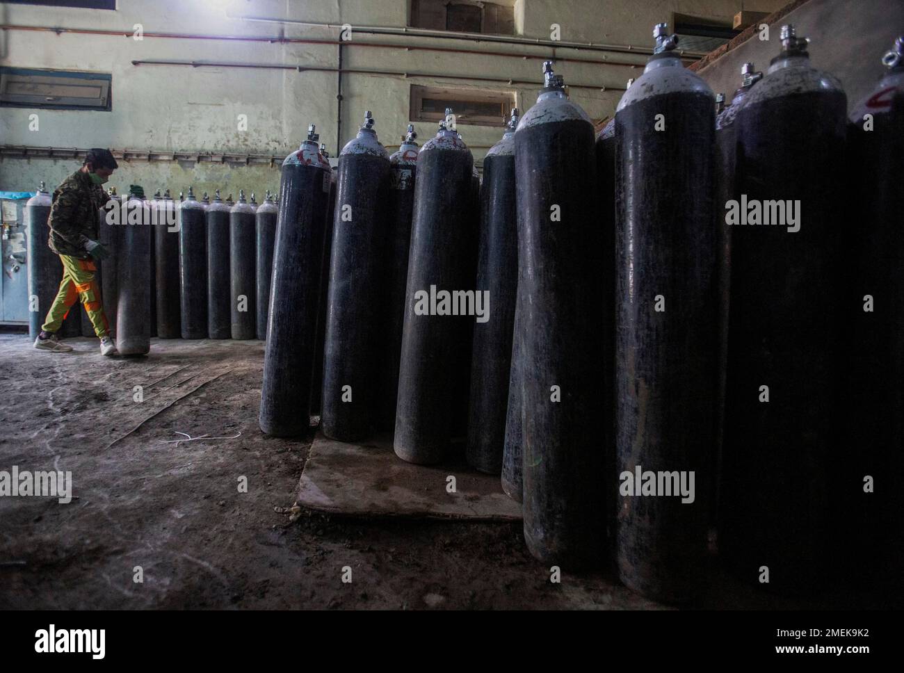 A Kashmiri worker moves an oxygen cylinder as they stock them inside a ...