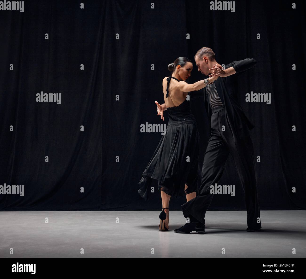 Man and woman, professional tango dancers performing in black stage ...